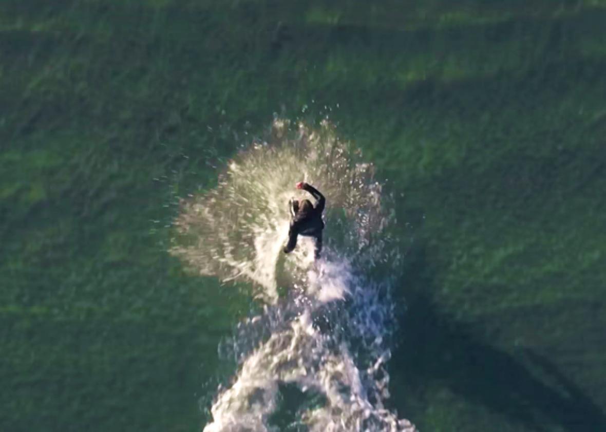 Overhead drone stunt video of a man running from one building to the next.